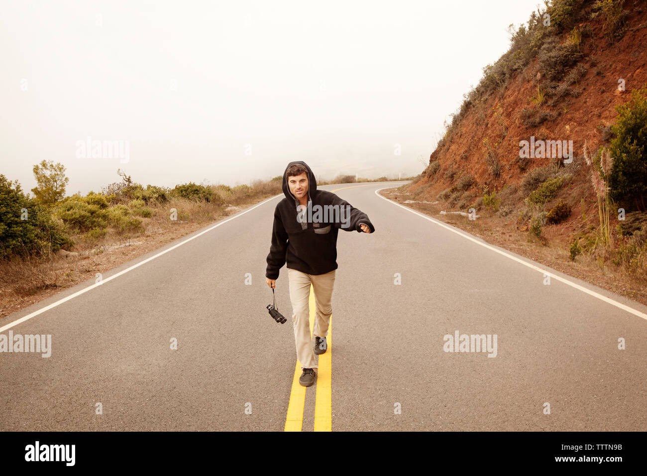 Portrait of man holding binocular while walking on mountain road Stock ...