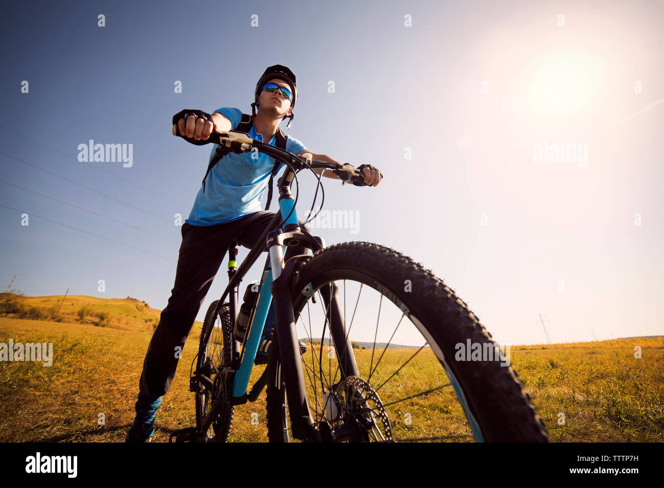 Low angle view of male athlete on bicycle in field against clear sky ...