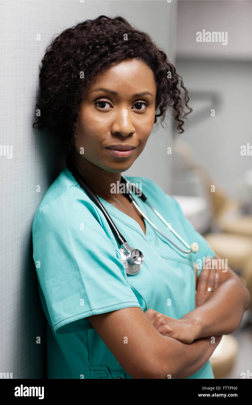 Portrait of female doctor standing against wall in hospital Stock Photo ...