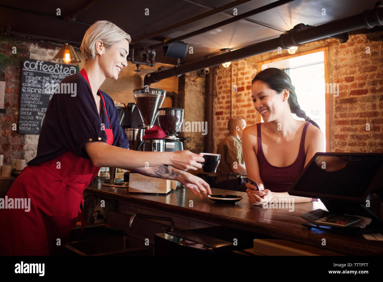 Side view of woman serving coffee to customer in cafe Stock Photo - Alamy