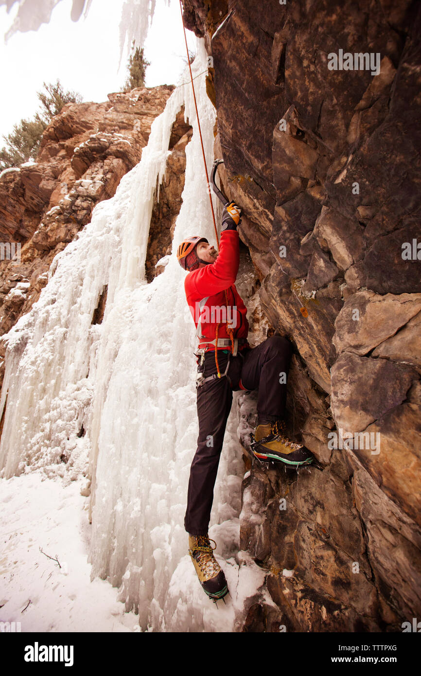 Full length of hiker climbing frozen waterfall Stock Photo - Alamy