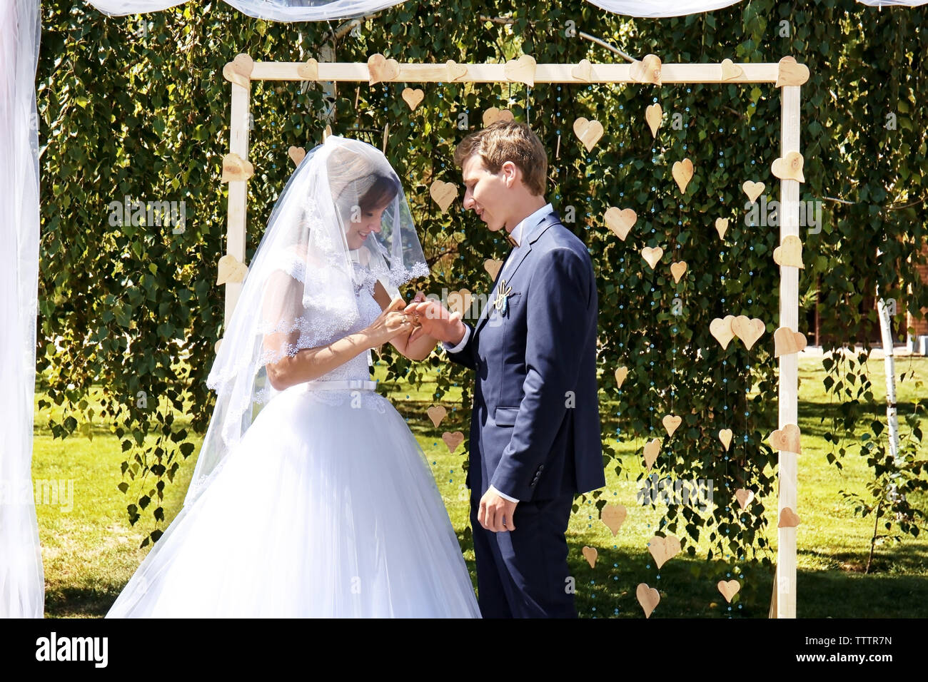 Newlyweds exchanging rings near altar outdoor Stock Photo - Alamy