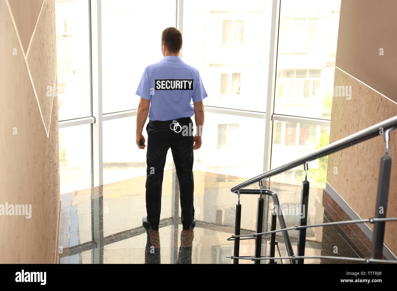 Security man standing beside window Stock Photo - Alamy