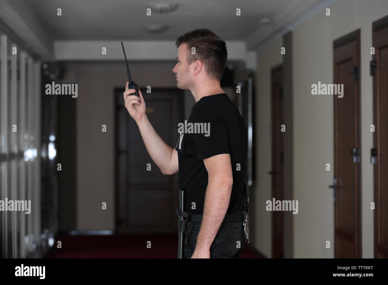 Security man standing indoors and using portable radio Stock Photo - Alamy