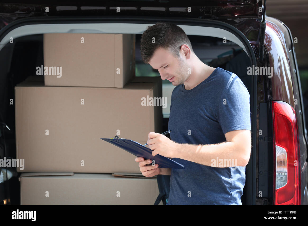 Young male deliverer noting executing of order Stock Photo - Alamy