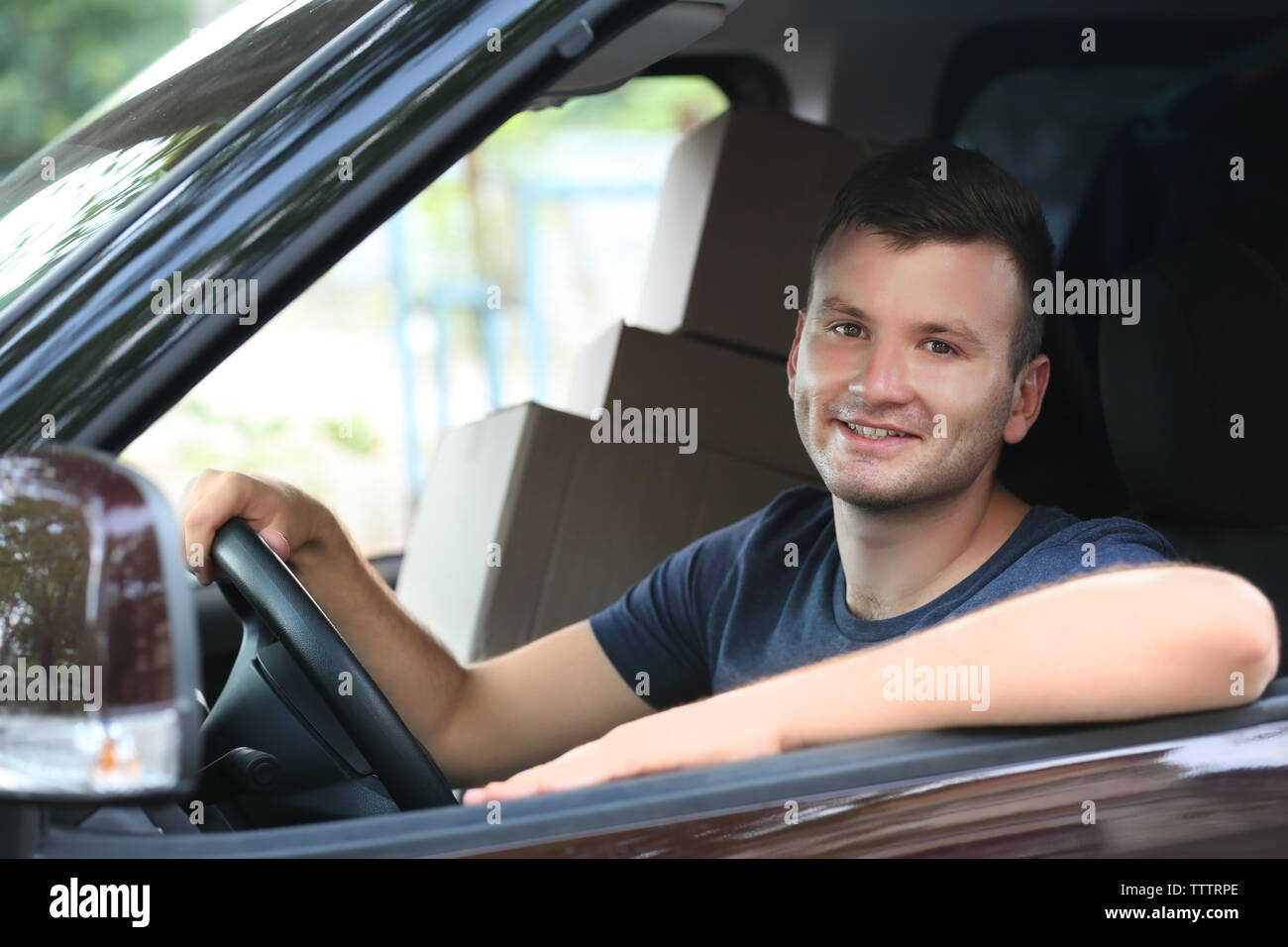Young male deliverer with boxes sitting in car Stock Photo - Alamy