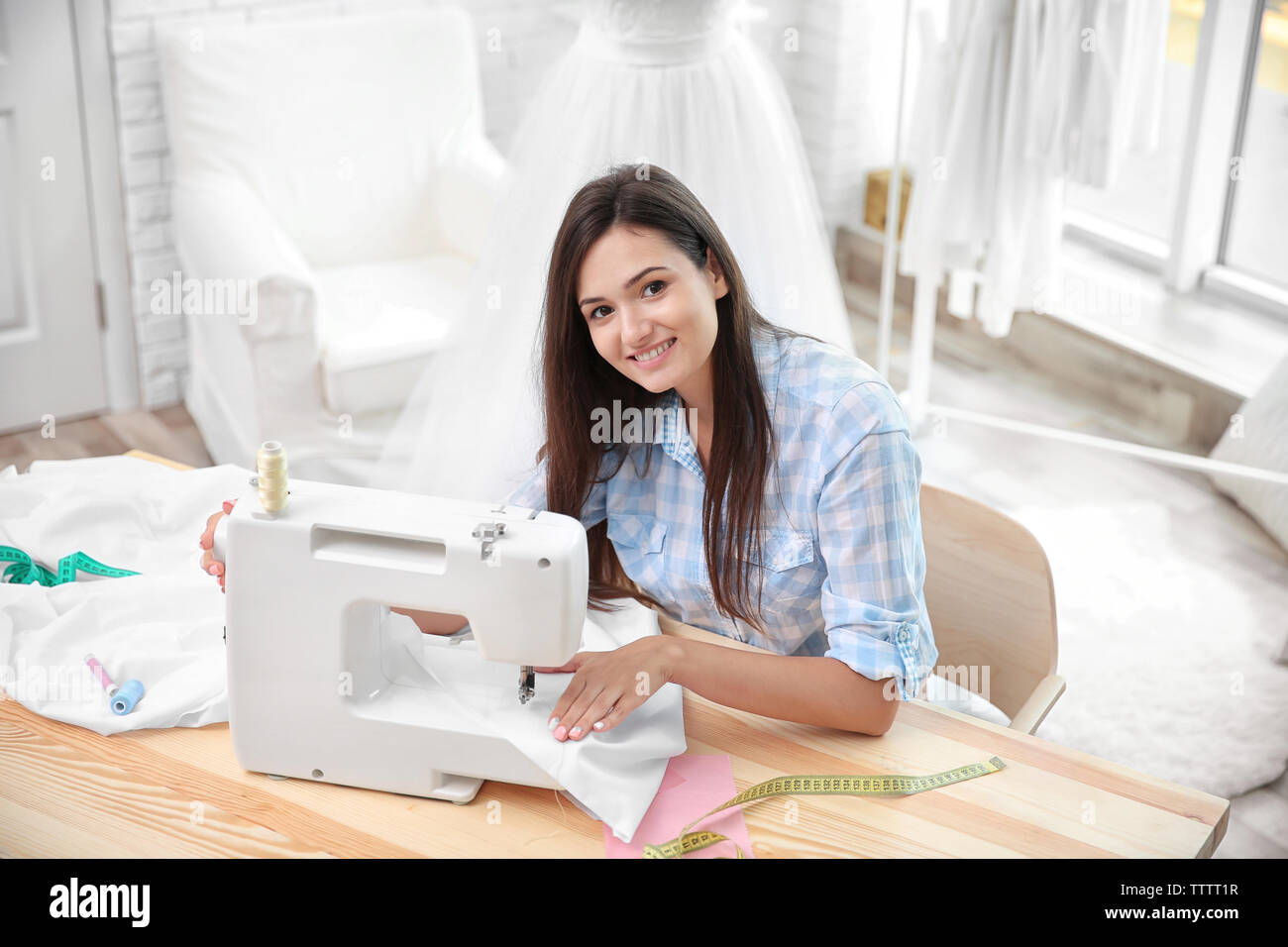 Pretty young dressmaker with sewing machine Stock Photo - Alamy