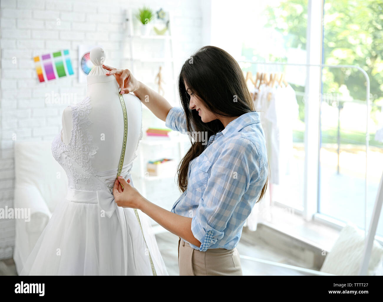 Pretty young woman near mannequin with wedding dress taking ...