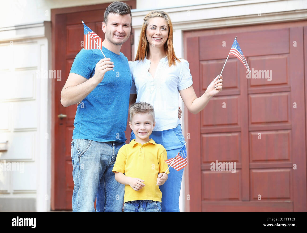 Happy family with little American flags beside home door Stock Photo ...