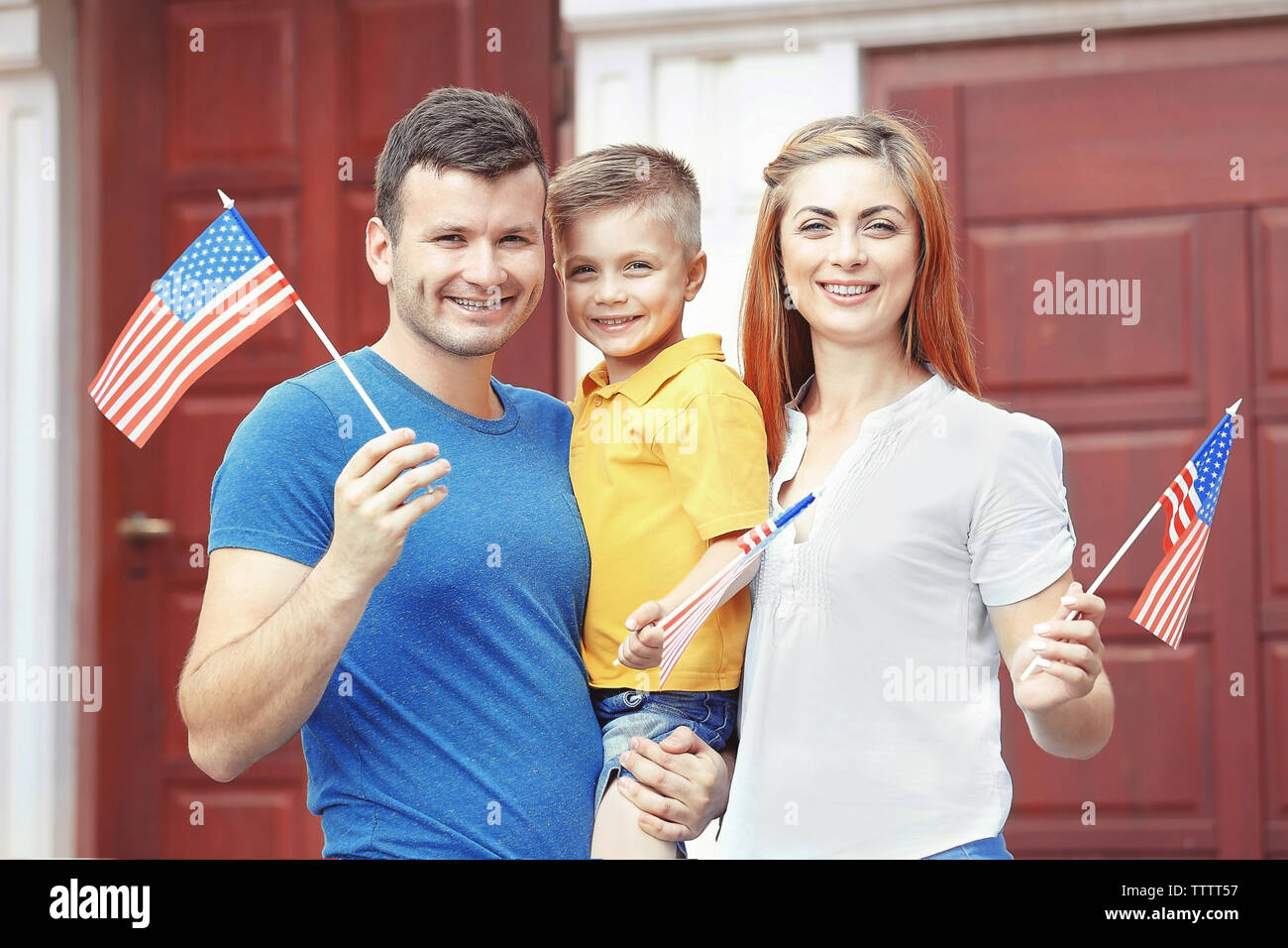 Happy family with little American flags beside home door Stock Photo ...