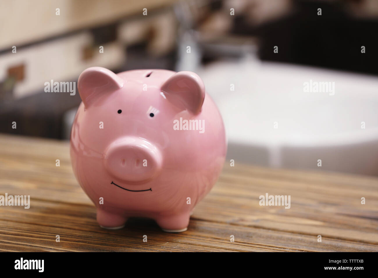 Pig money box on blurred kitchen sink background. Saving water concept ...