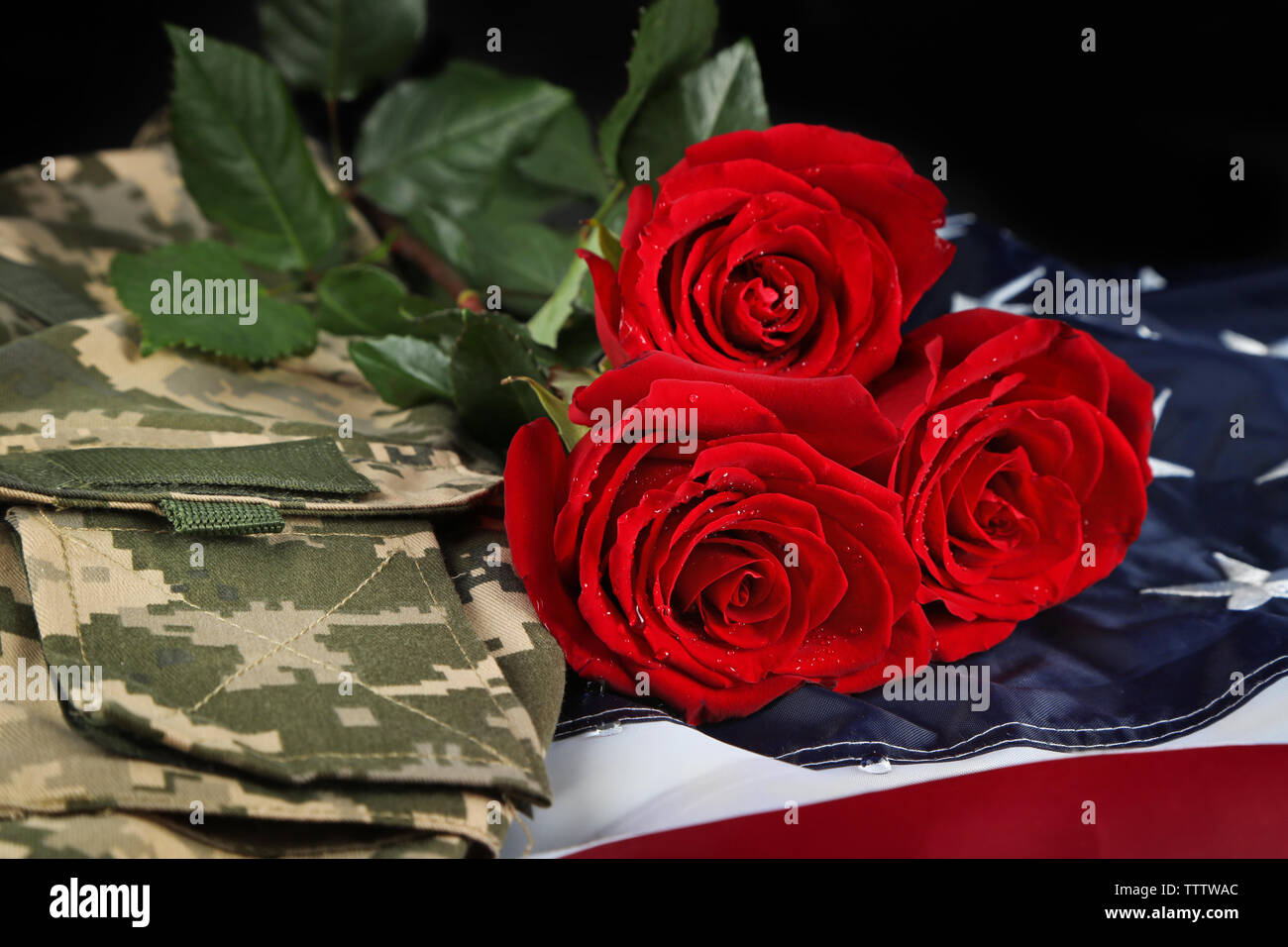 Red roses on American flag with military uniform, closeup Stock Photo ...