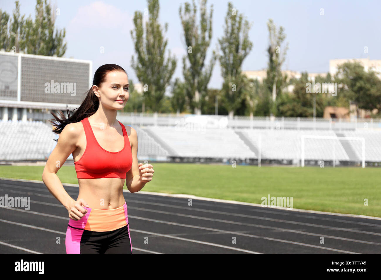 Pretty young woman running at stadium Stock Photo - Alamy