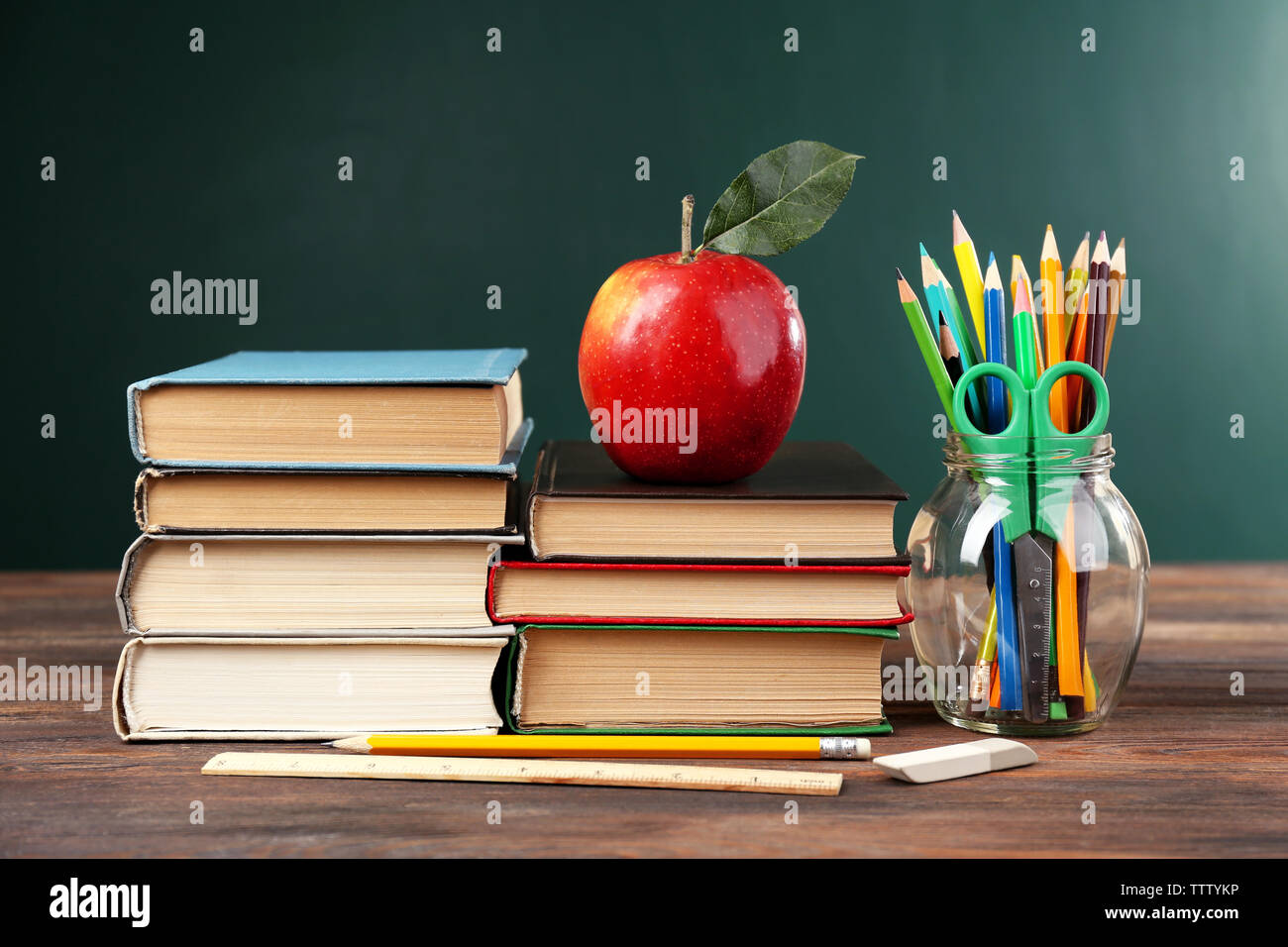 School books with stationery and apple on blackboard background Stock ...
