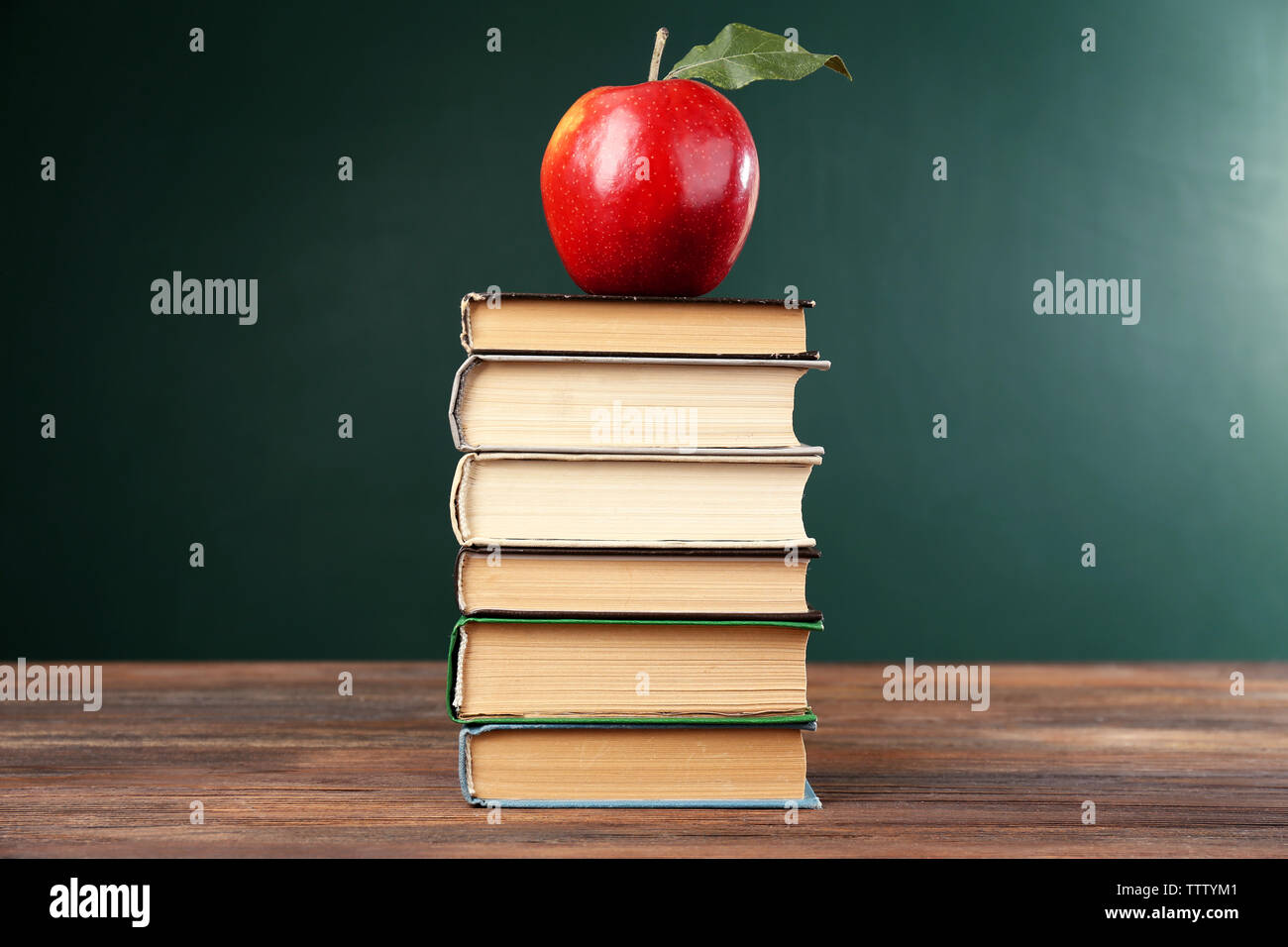 School books with apple on blackboard background Stock Photo - Alamy