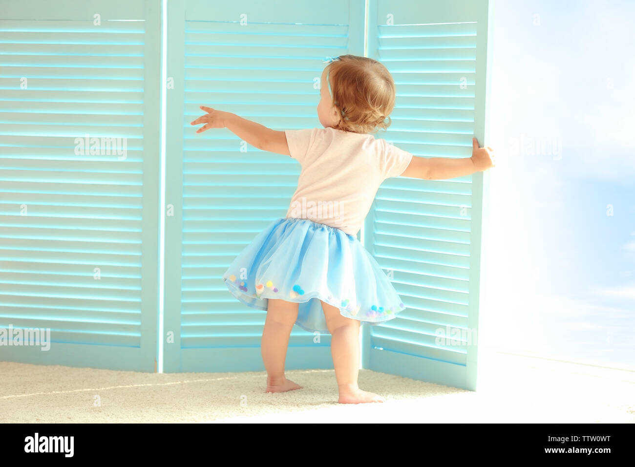 Baby girl in a beautiful dress posing near the blue screen Stock Photo ...
