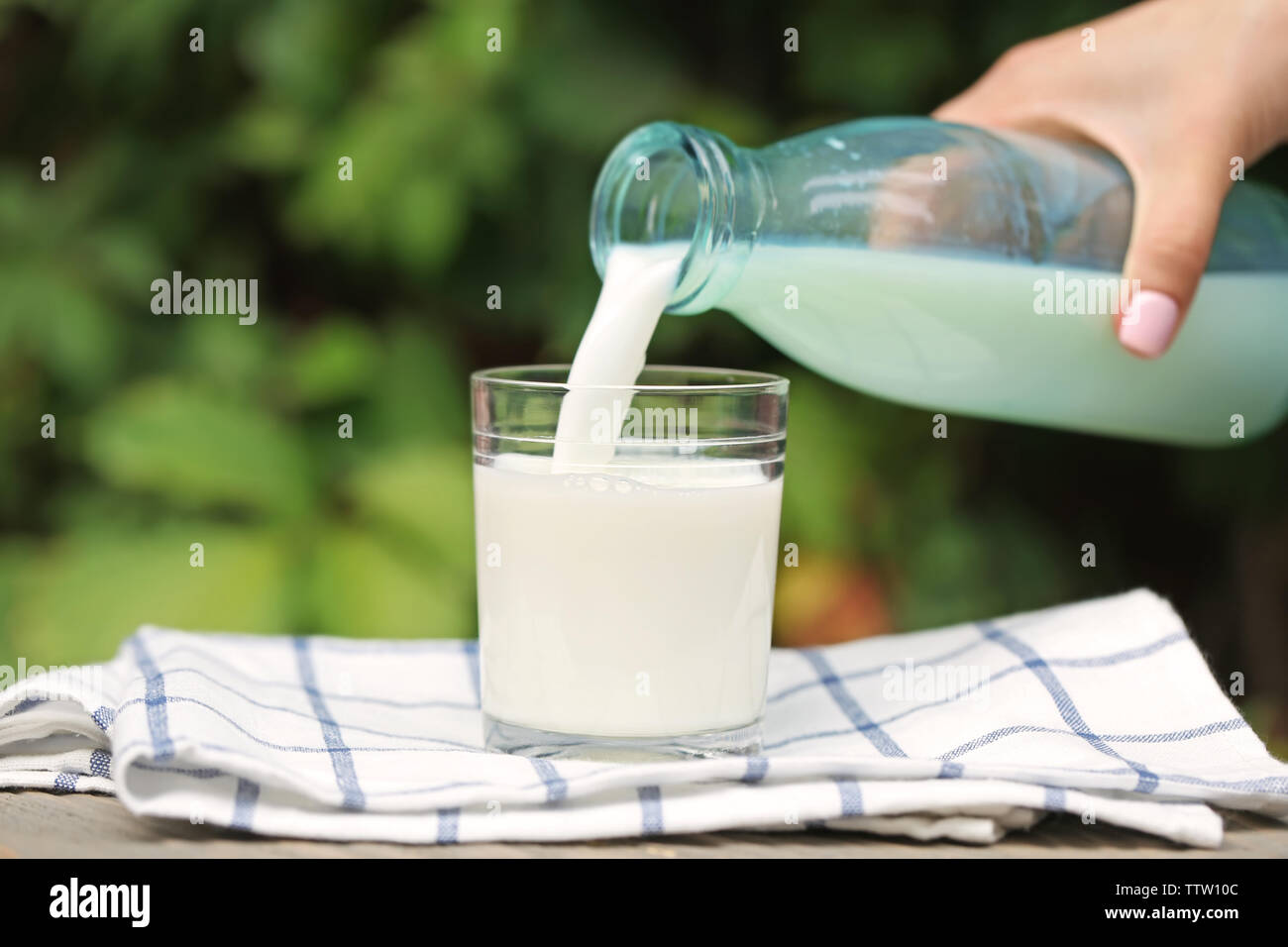 Female hand pouring milk from a bottle into a glass, outdoors Stock ...