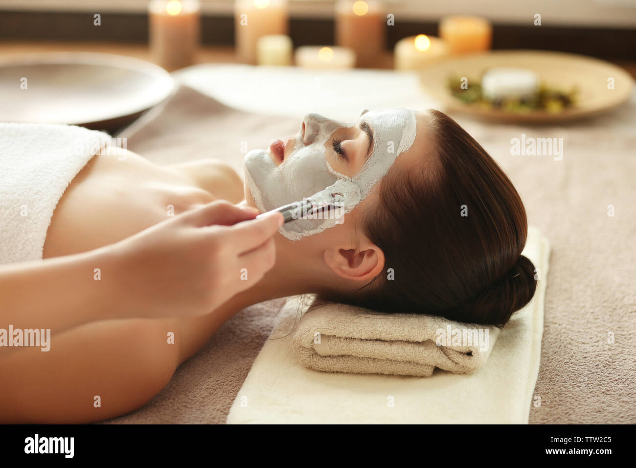 Spa concept. Hand applying nourishing mask on female face in spa salon ...