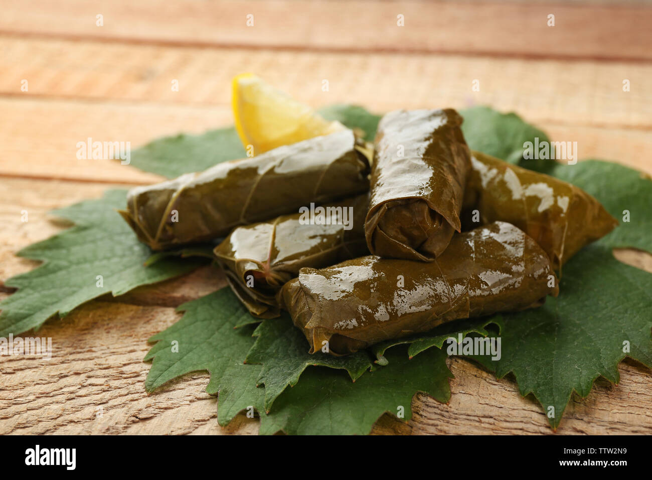 Stuffed delicious Dolma with lemon on vine leaf and wooden background ...