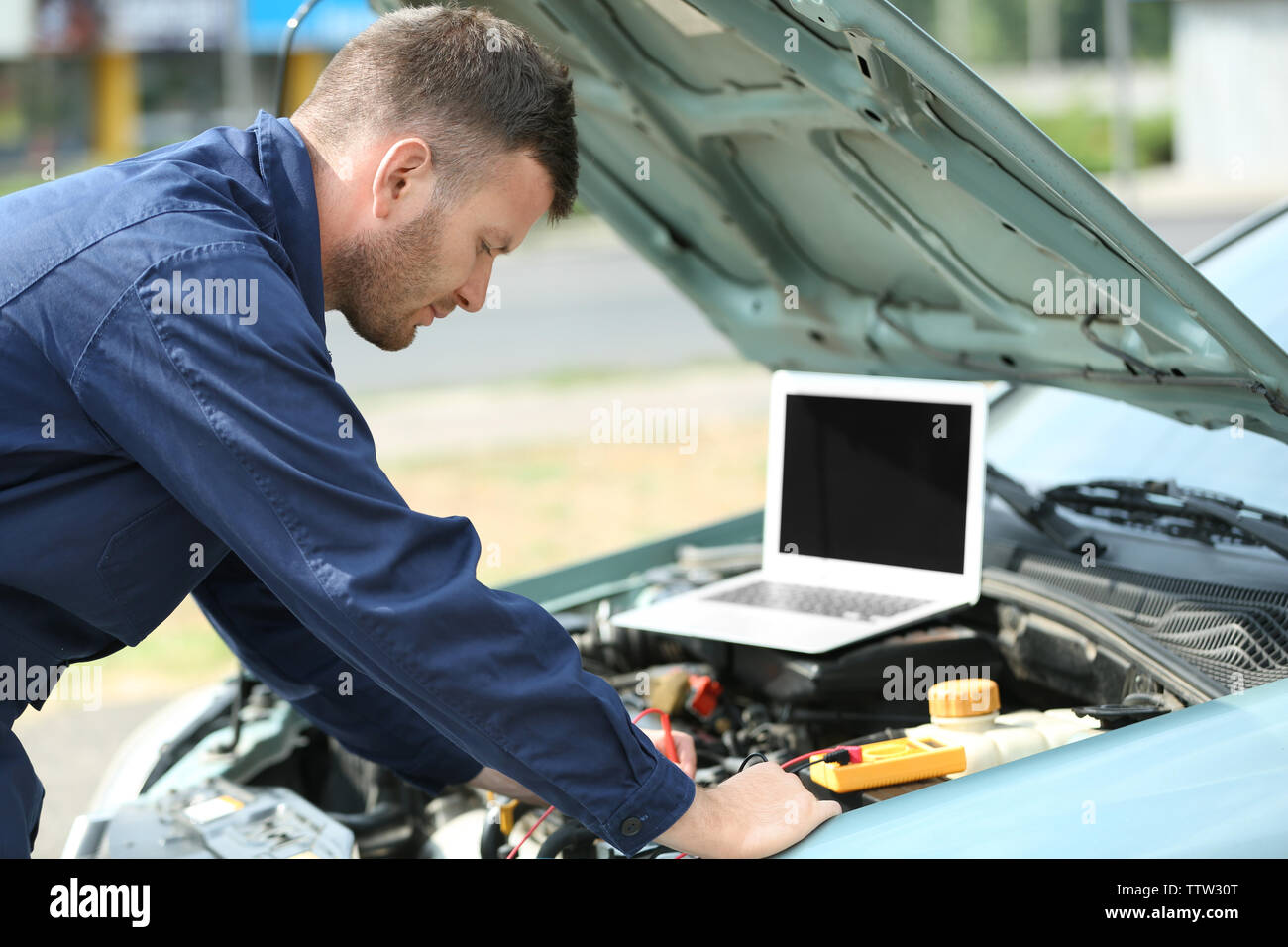 Mechanic using computer diagnostics while repairing car Stock Photo - Alamy