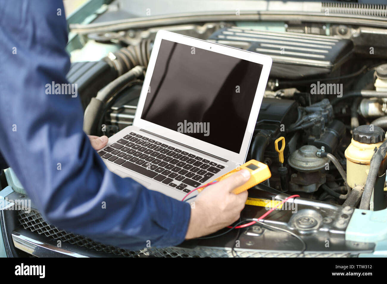 Mechanic using computer diagnostics while repairing car Stock Photo - Alamy