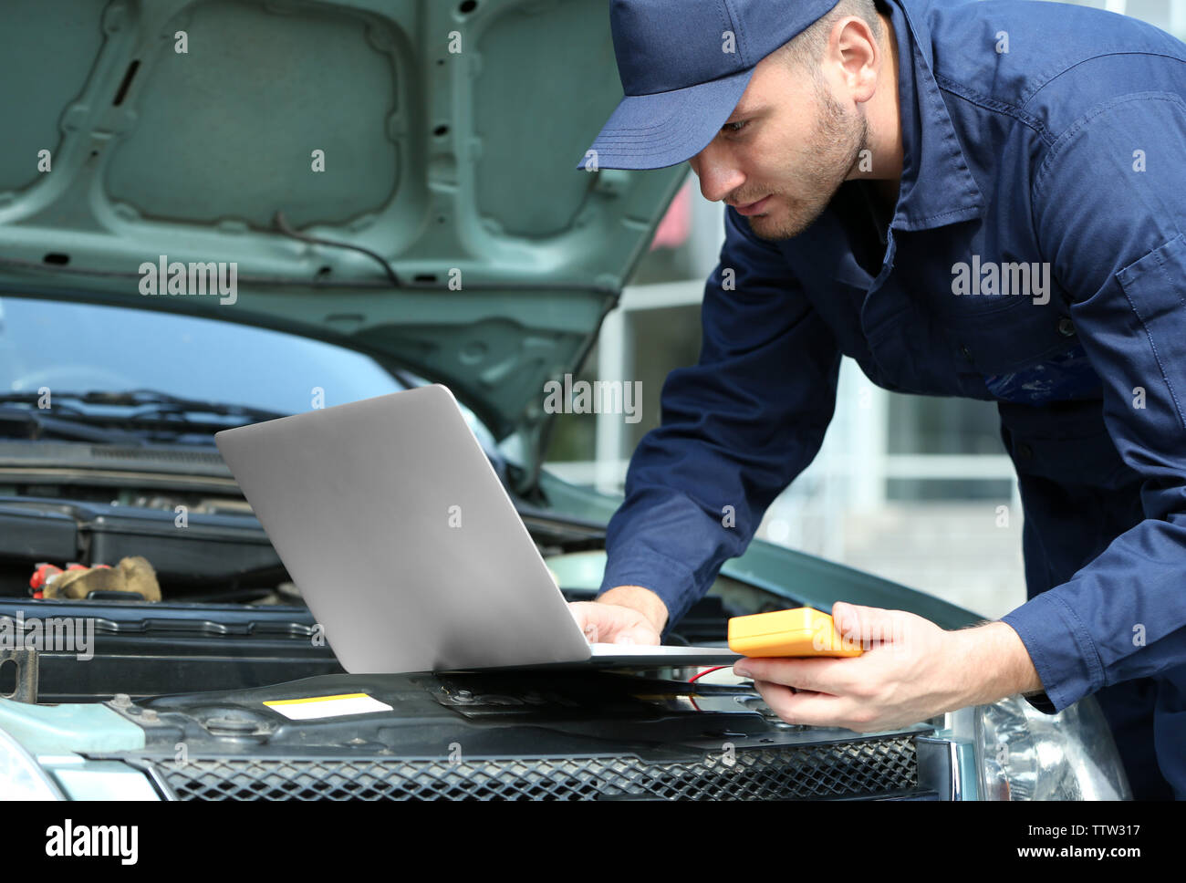 Mechanic using computer diagnostics while repairing car Stock Photo - Alamy