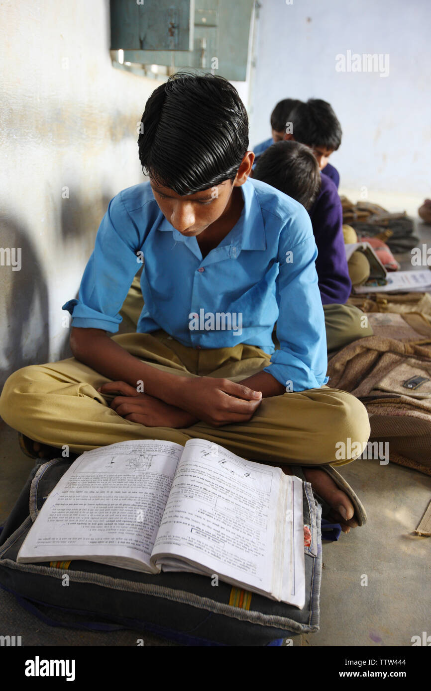Indian schoolboy reading a book in a classroom Stock Photo - Alamy