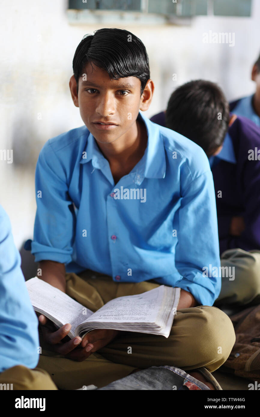 Indian schoolboy reading a book in a classroom Stock Photo - Alamy