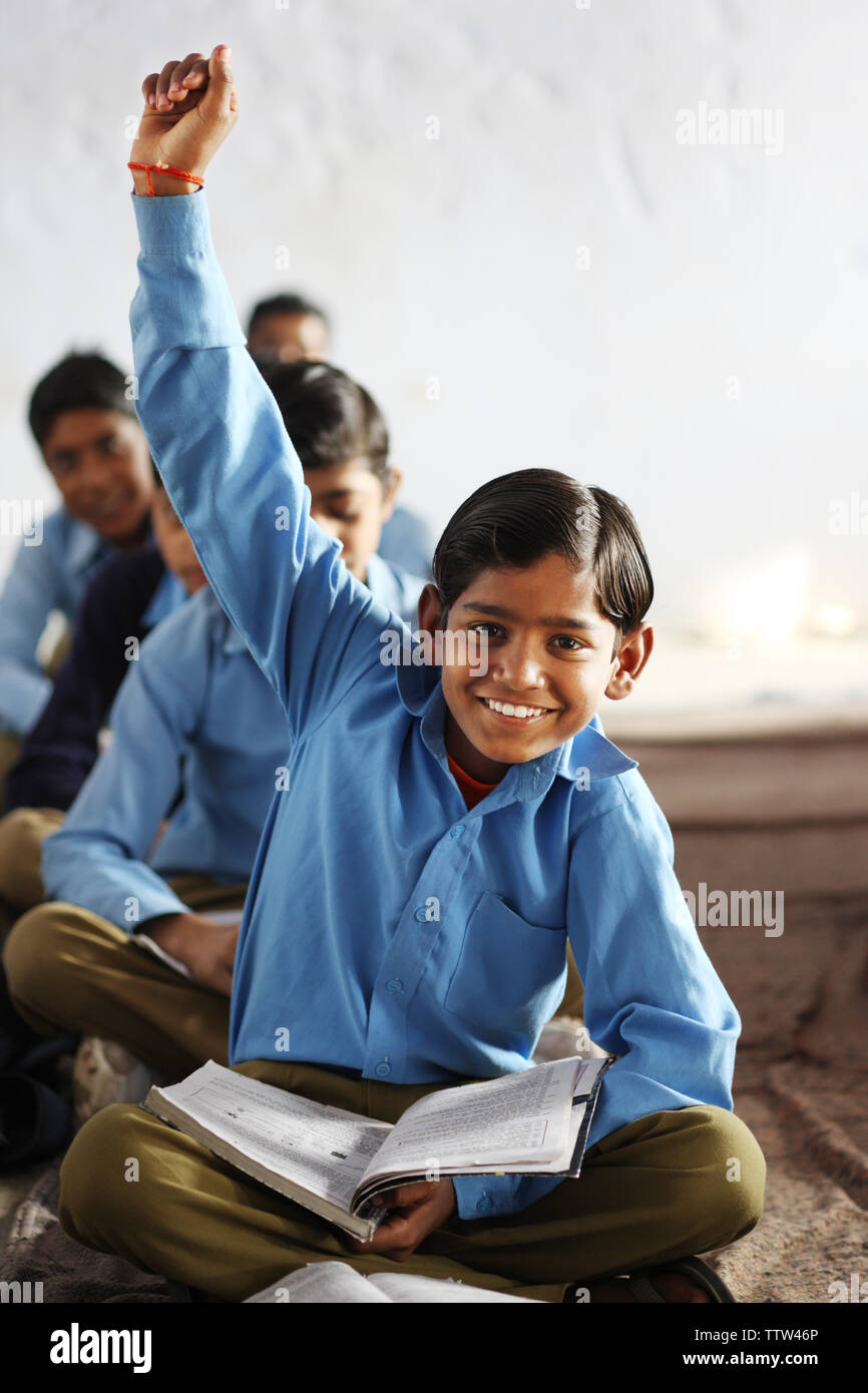 Boy raising hand in a classroom Stock Photo - Alamy