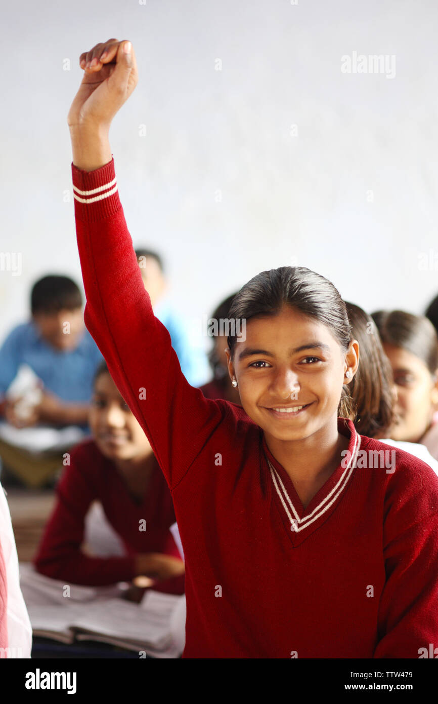Girl raising hand in a classroom Stock Photo - Alamy