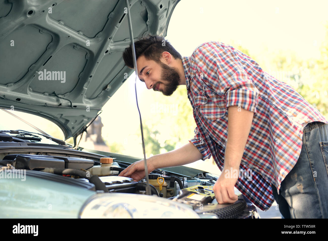 Young handsome man looking under car hood Stock Photo - Alamy