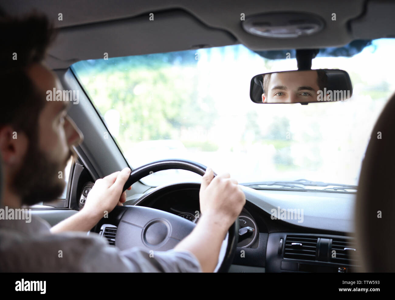 Young successful driver looking in rear view mirror Stock Photo - Alamy