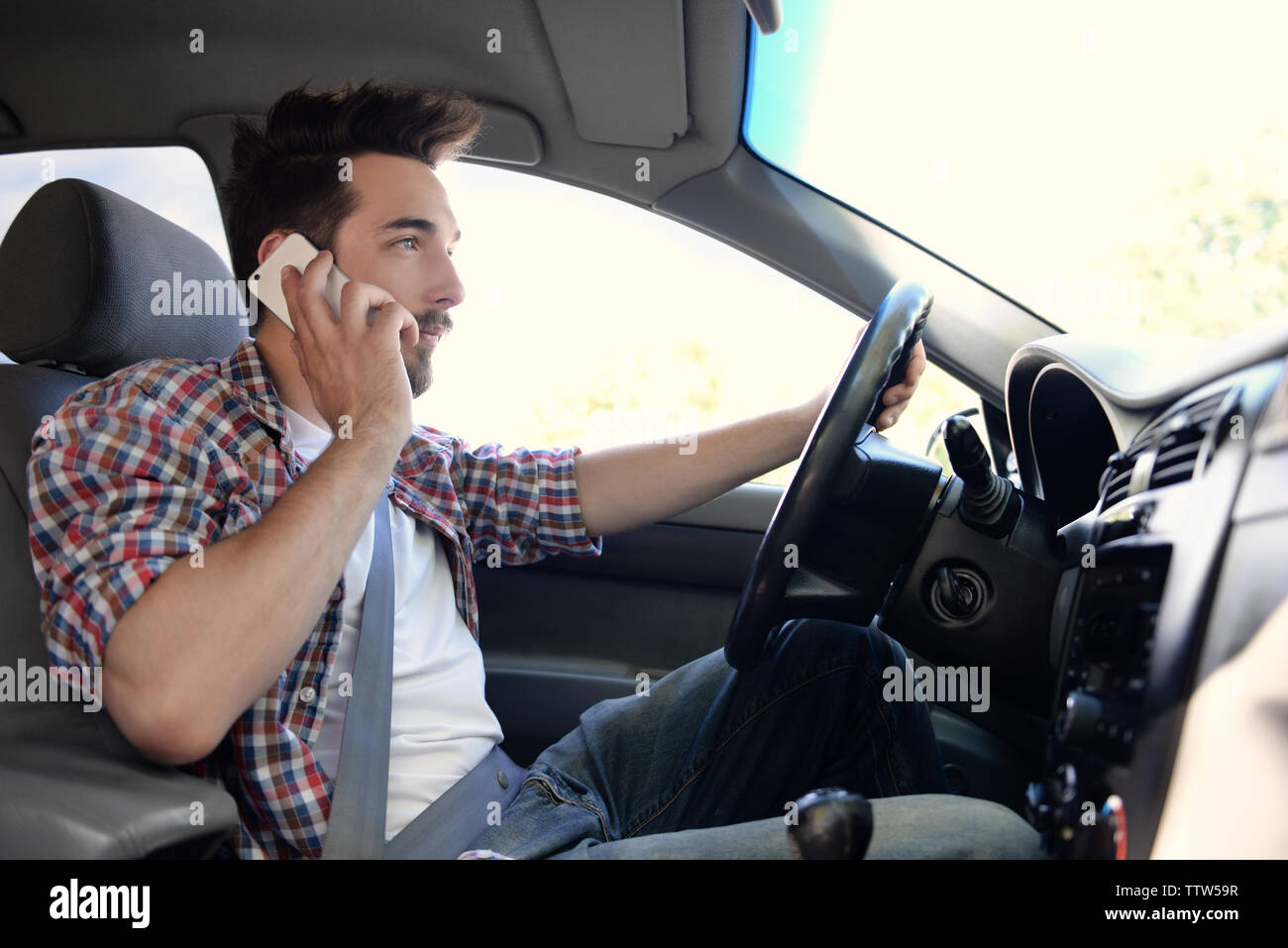 Young handsome driver using mobile phone while driving car Stock Photo ...