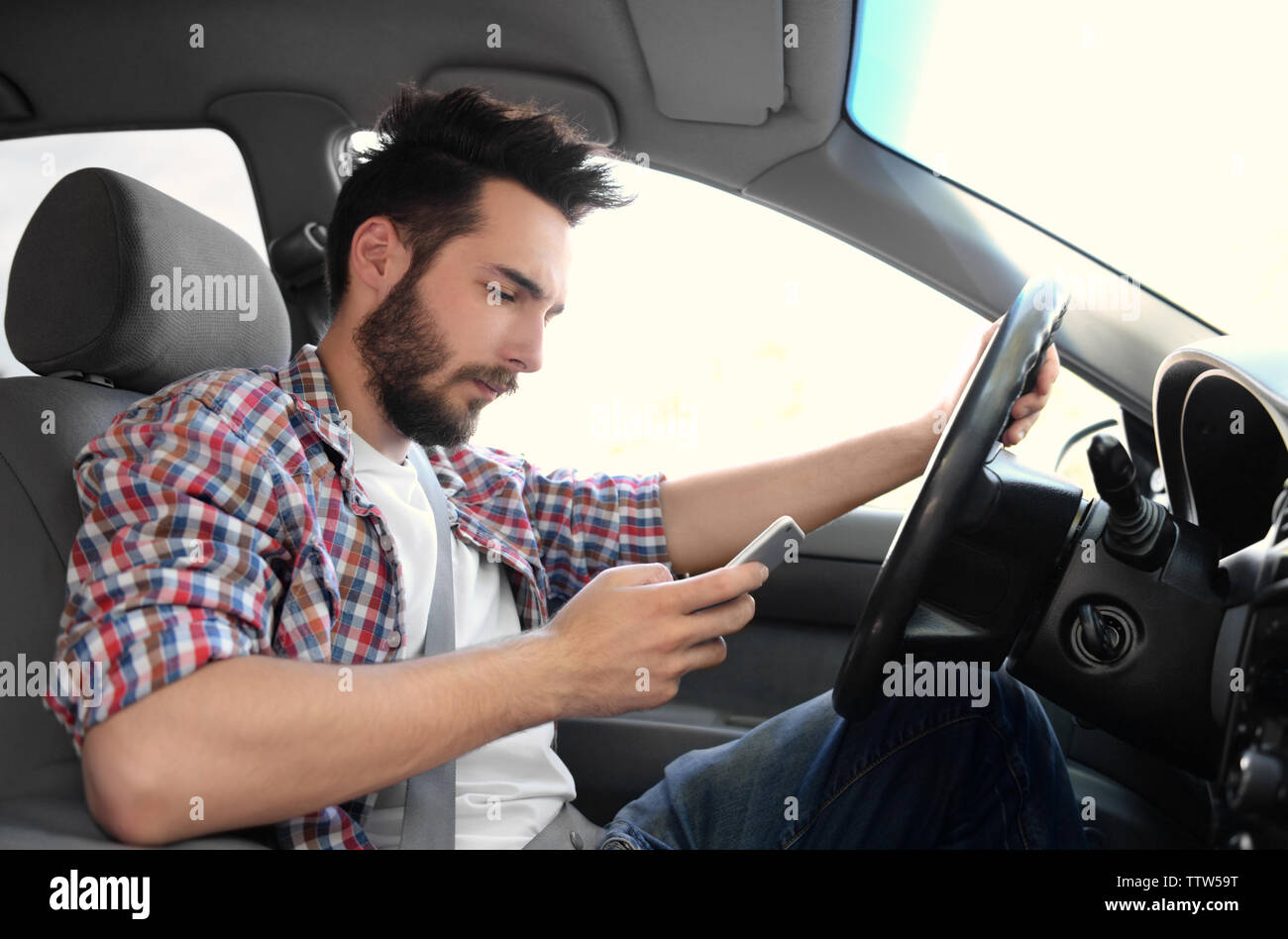 Young handsome driver using mobile phone while driving car Stock Photo ...