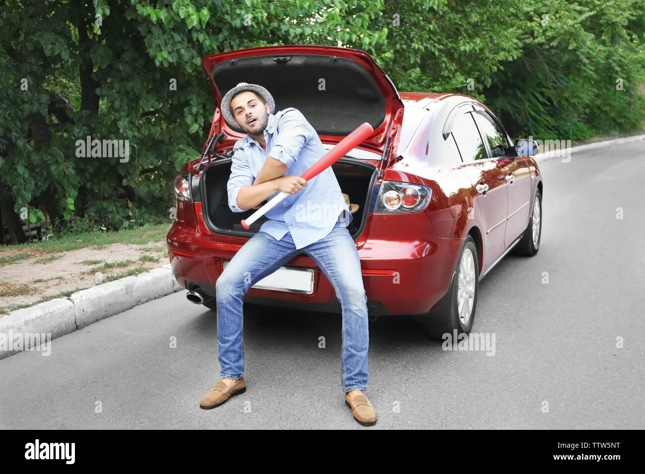 Handsome young man with baseball bat sitting in car trunk Stock Photo ...