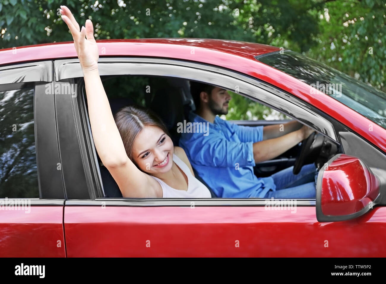 Pretty young woman waving through open car window Stock Photo - Alamy