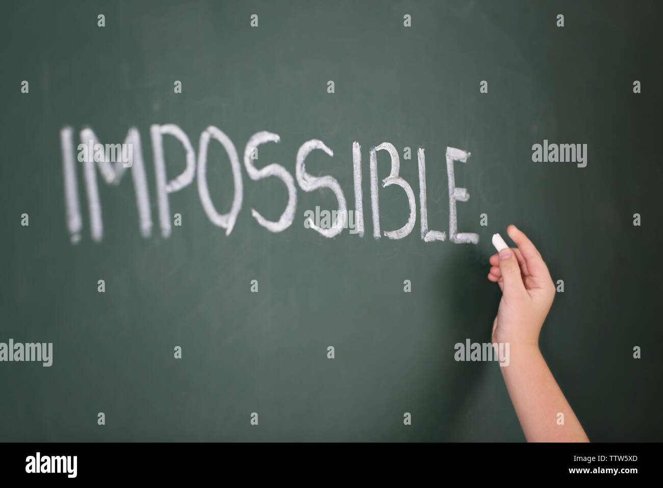 Little girl writing word impossible on chalkboard Stock Photo - Alamy