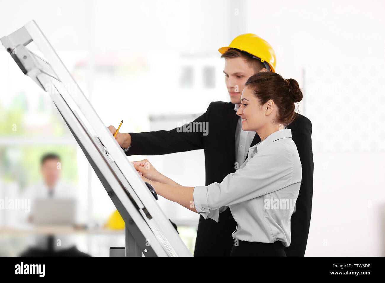 Two young creative engineers working with project on drawing board ...