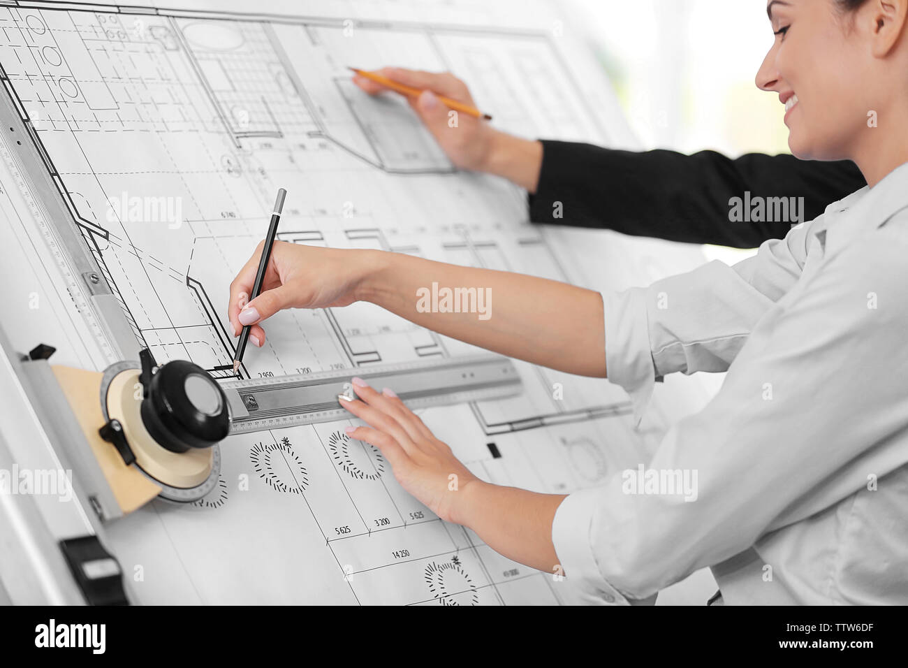 Two young creative engineers working with project on drawing board ...