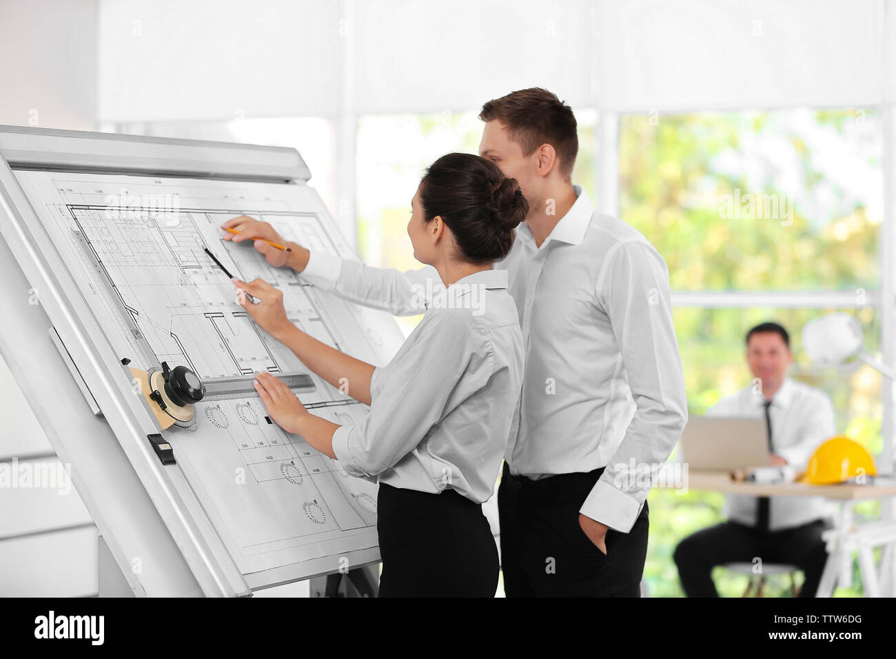 Two young creative engineers working with project on drawing board ...