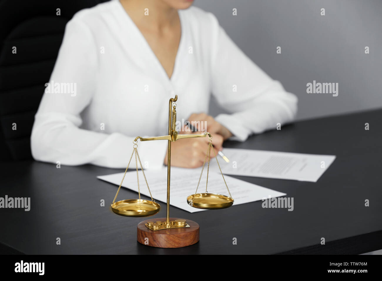 Scales of justice and businesswoman sitting at table Stock Photo - Alamy