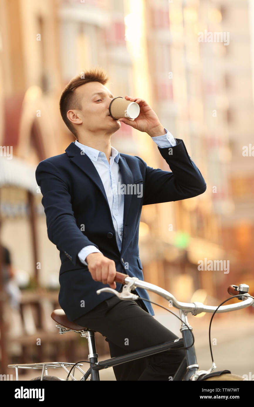 Coffee-to-go concept. Young man with bicycle and cup of coffee on ...