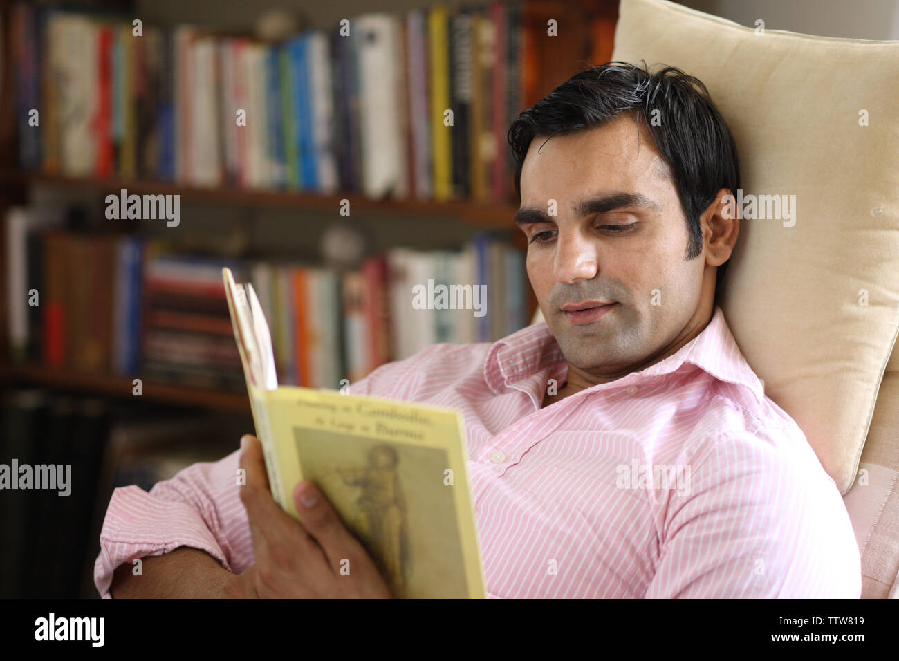 Man reading a book on a reclining chair Stock Photo - Alamy