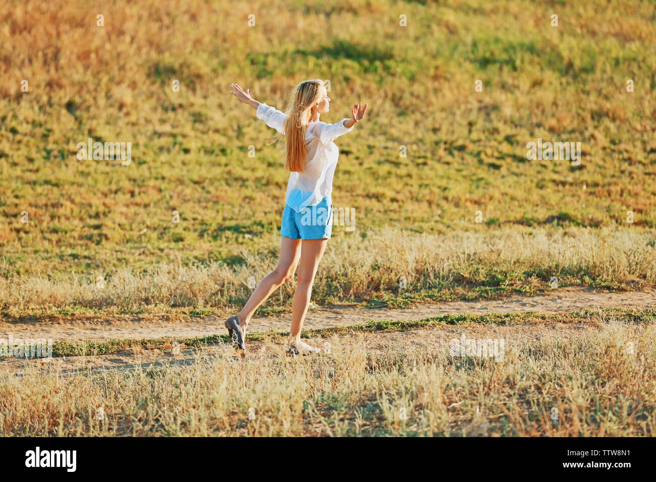Young woman walking on field background Stock Photo - Alamy