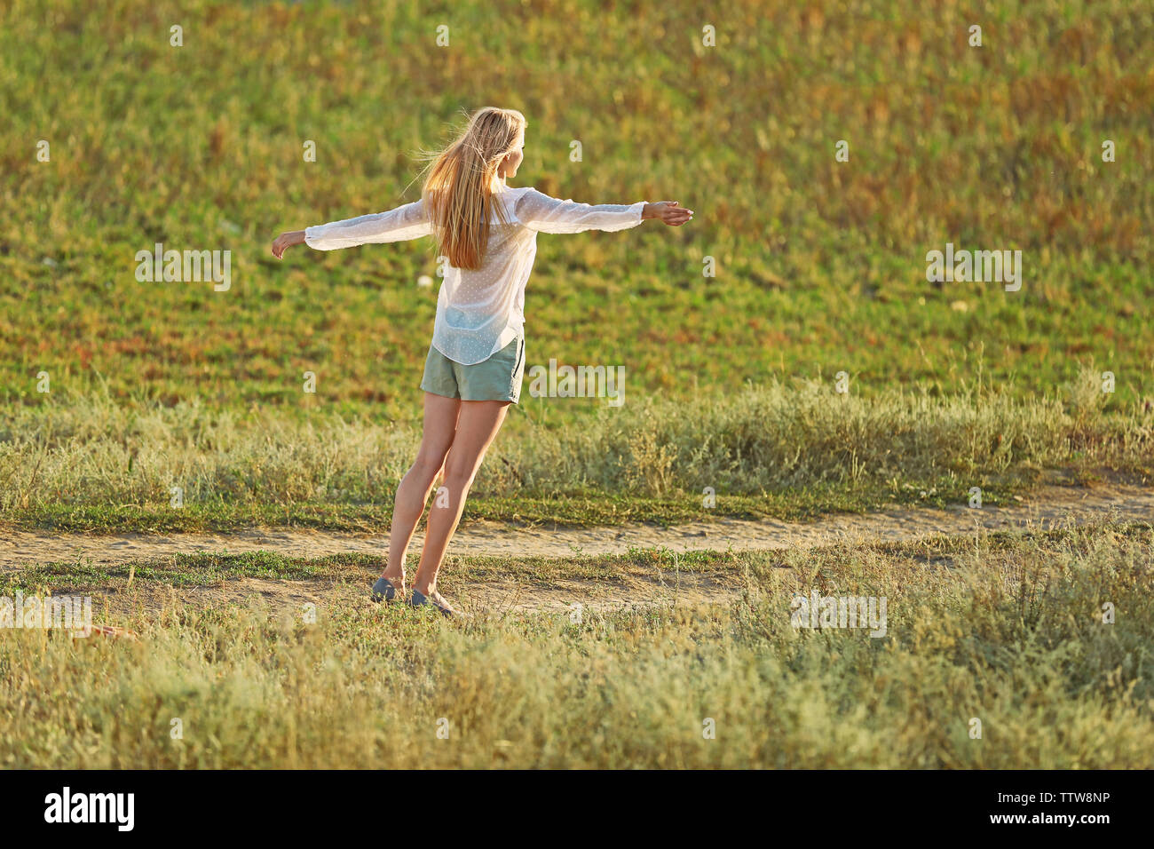 Young woman walking on field background Stock Photo - Alamy