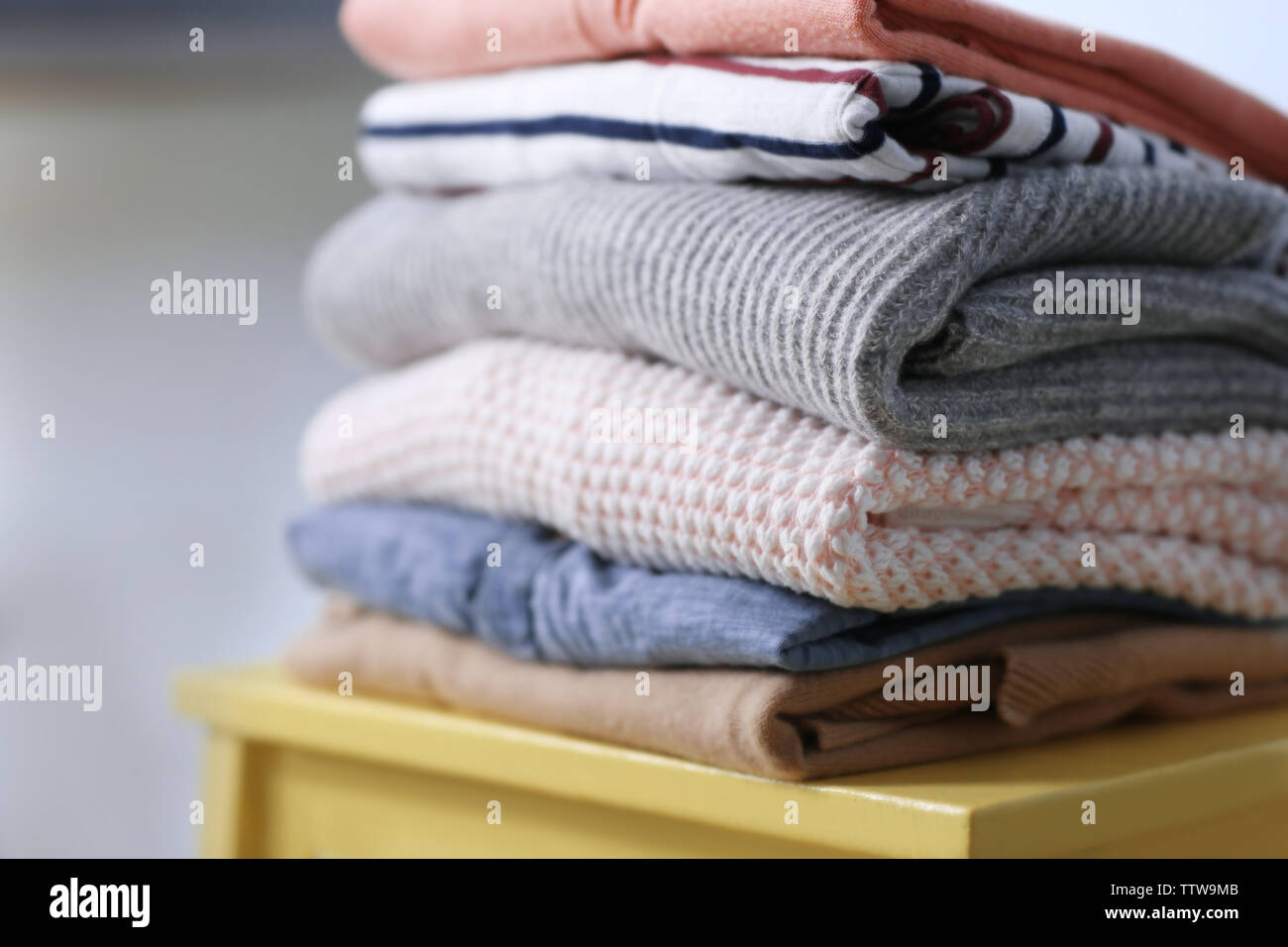 Pile of clothes on yellow stool Stock Photo - Alamy