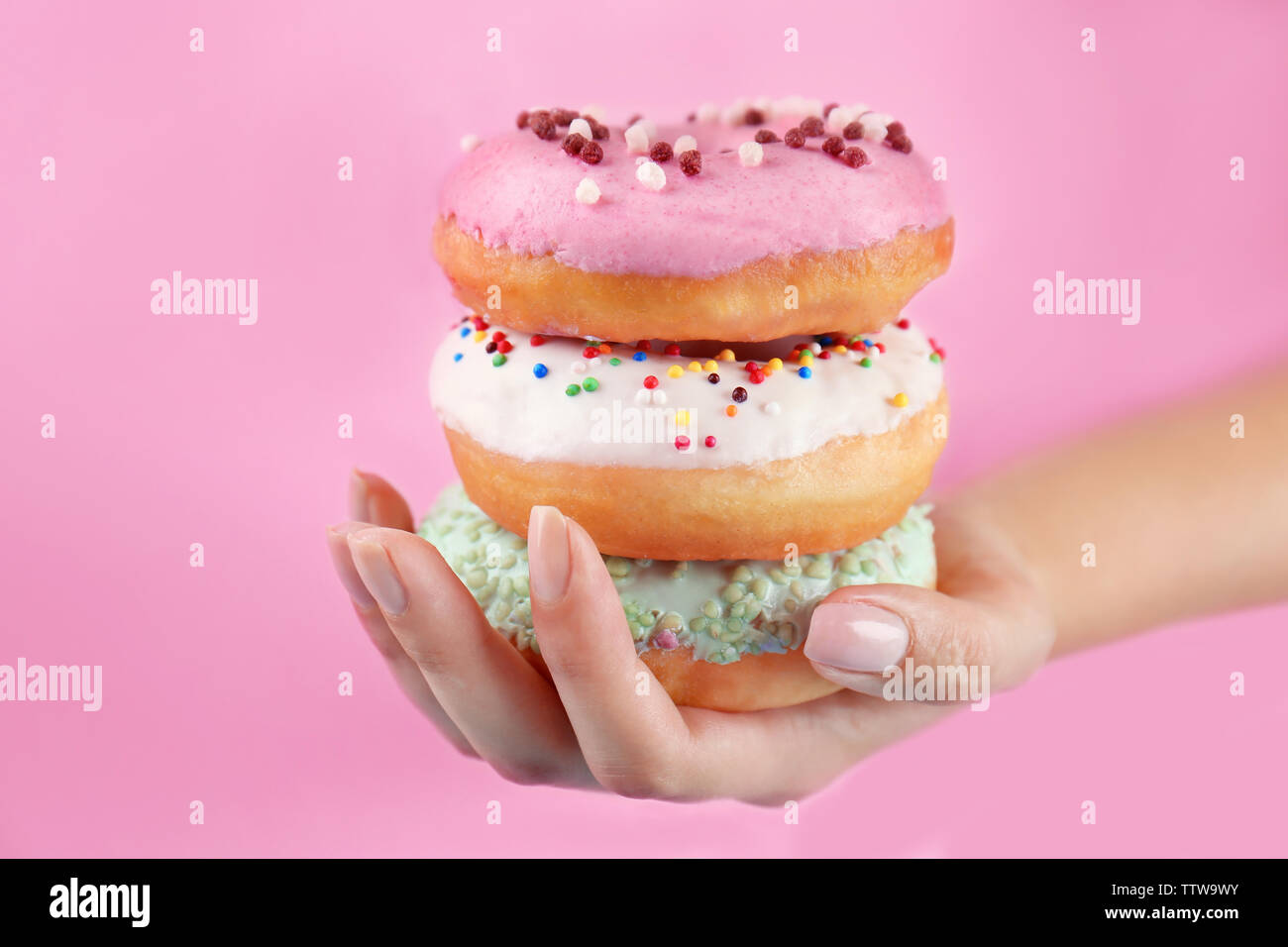 Female hand holding stack of delicious donuts, closeup Stock Photo - Alamy