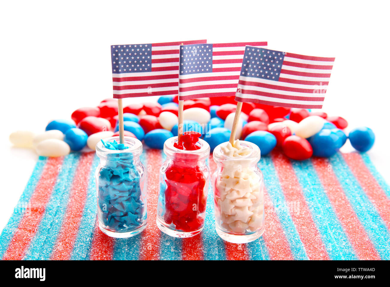 Glass jars with sweets and little American flags on white background ...