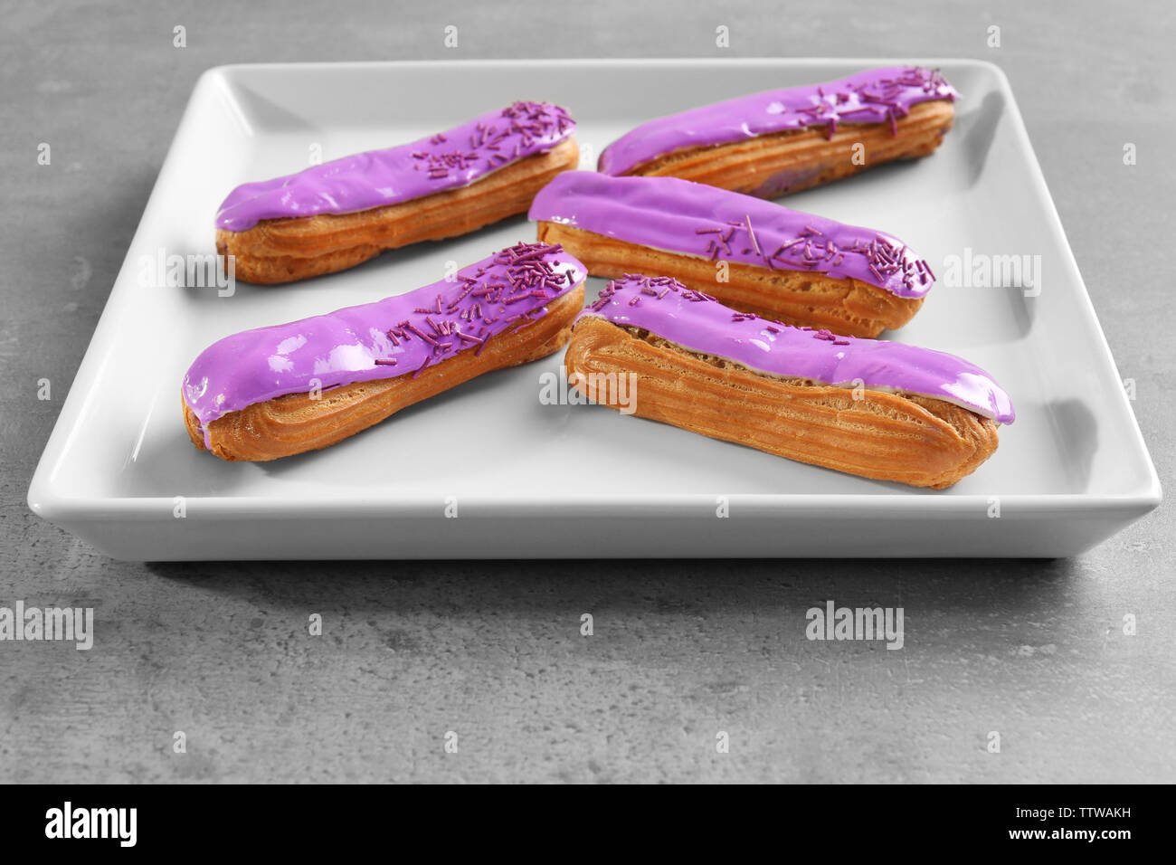 White tray with delicious glazed eclairs on light textured background ...