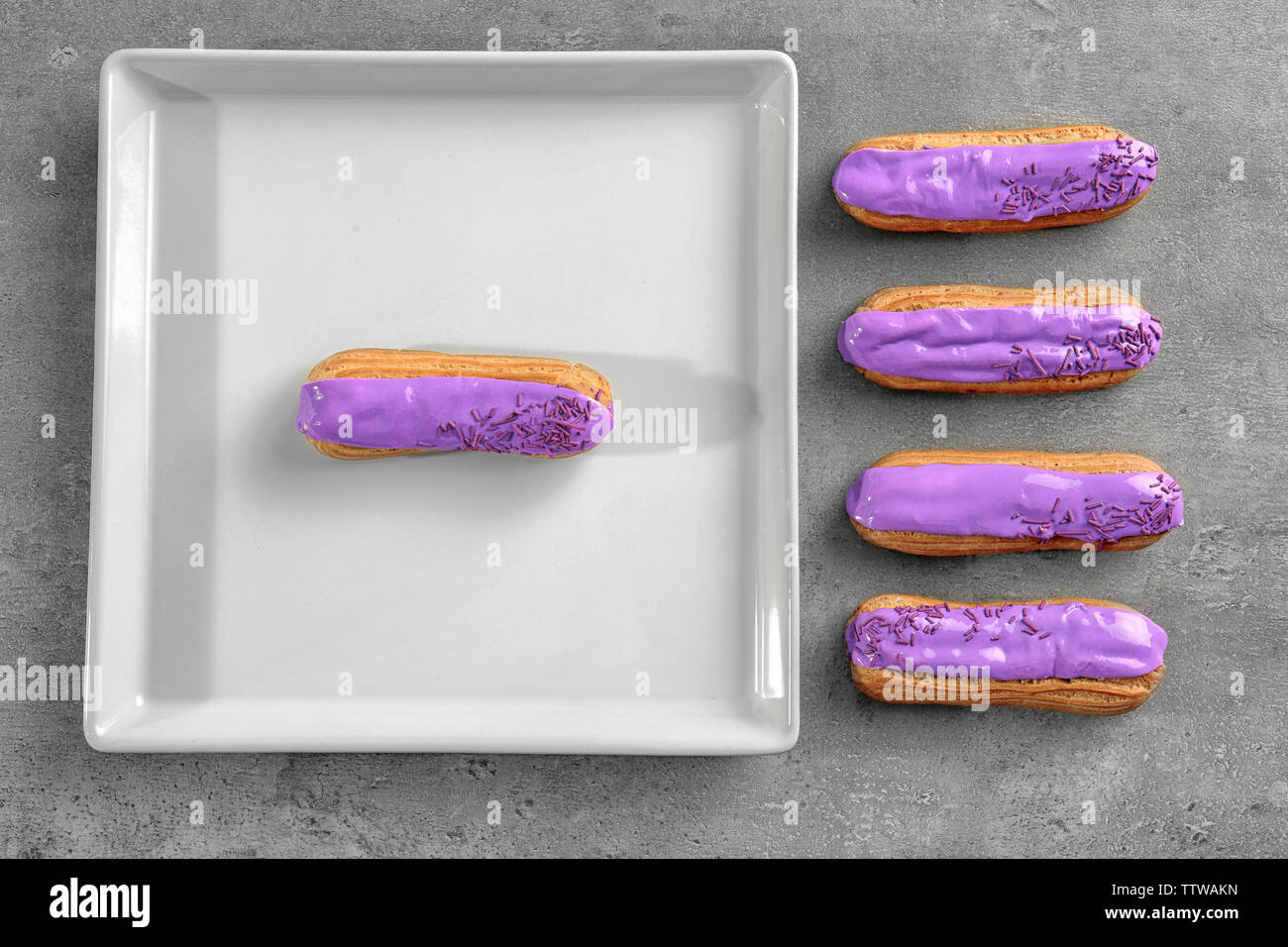 White tray and delicious glazed eclairs on light textured background ...